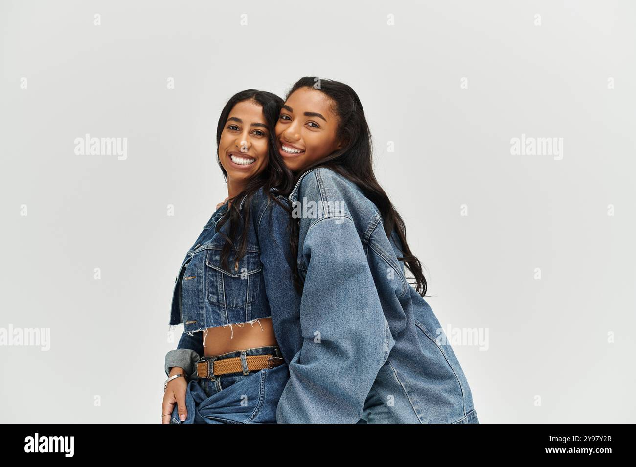 Two stylish young women pose closely, showing off their denim outfits ...