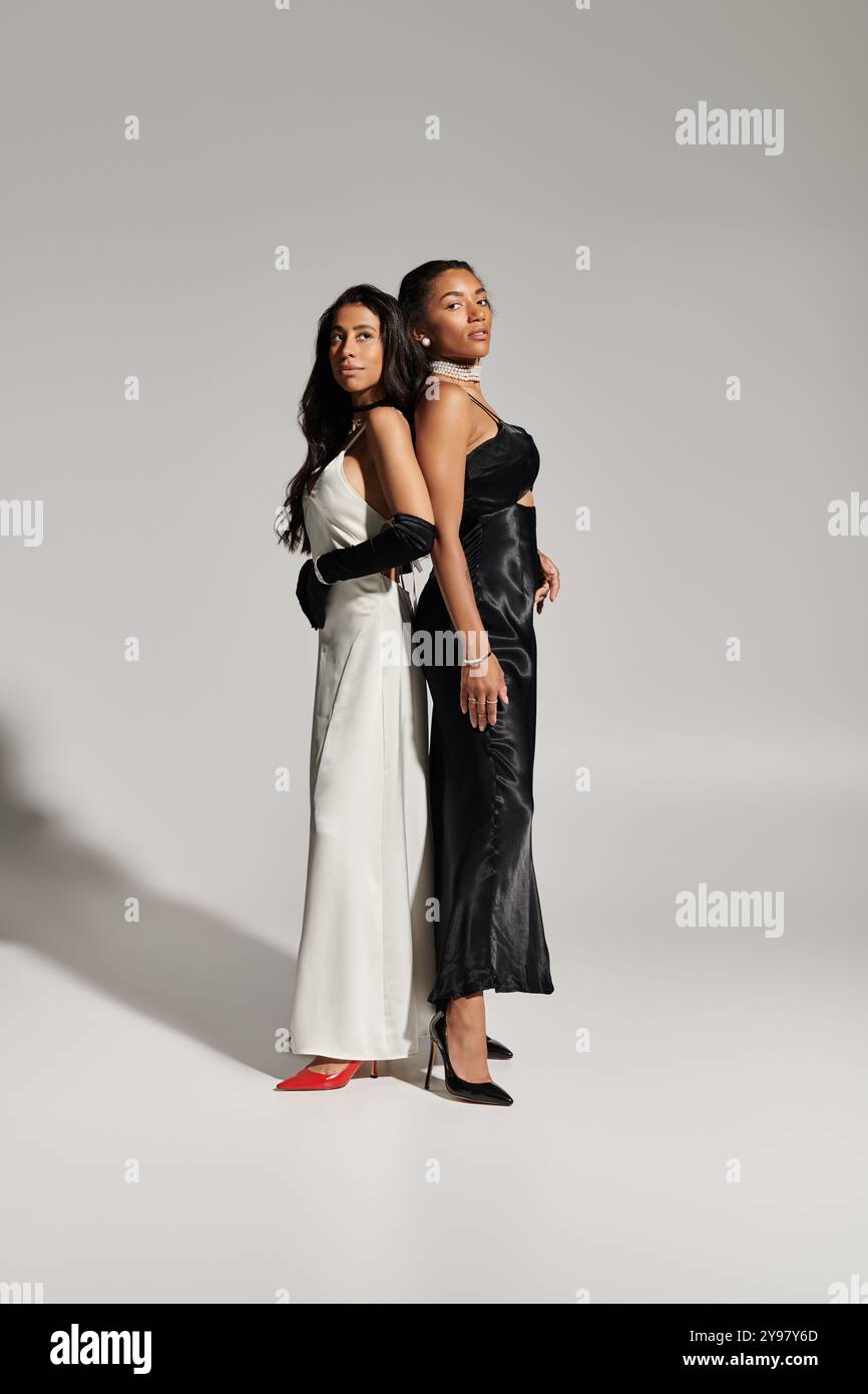 Two young women in stylish attire stand back to back, exuding ...