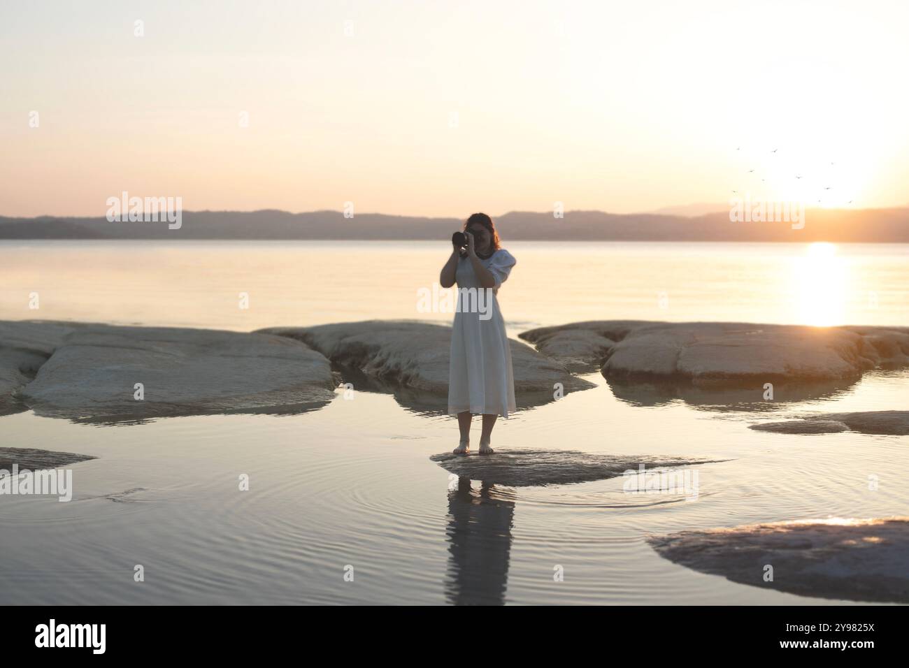 young woman photographing a seascape with sunset Stock Photo - Alamy