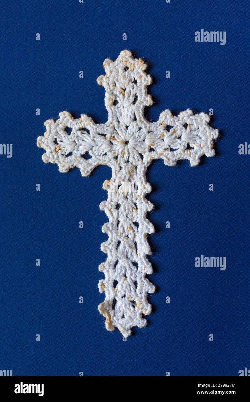 old crocheted cross on blue background Stock Photo - Alamy