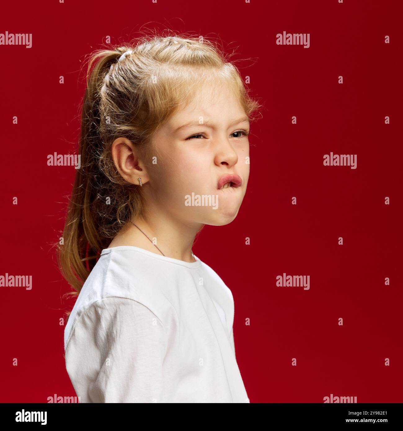 Portrait of little girl crunched face, makes funny expression, giving ...