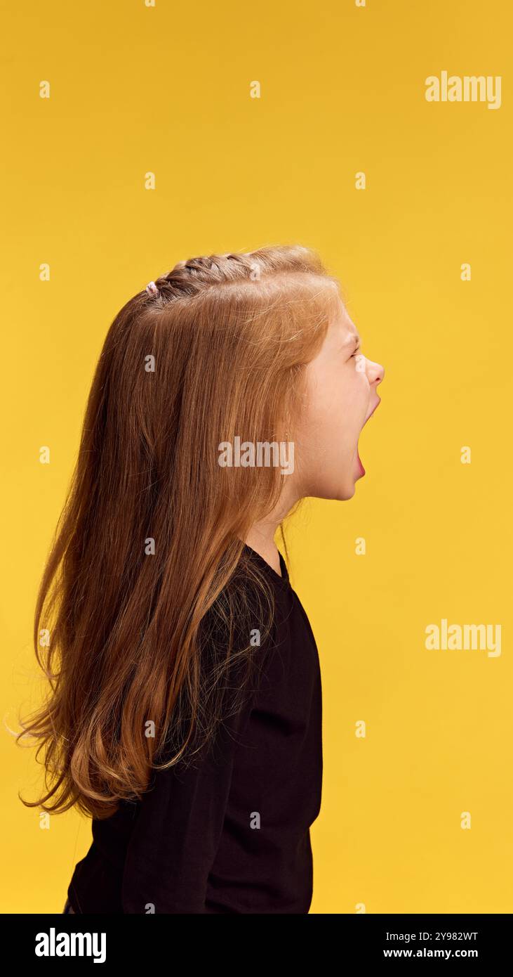 Side profile of girl screaming loudly, her mouth wide open,against ...