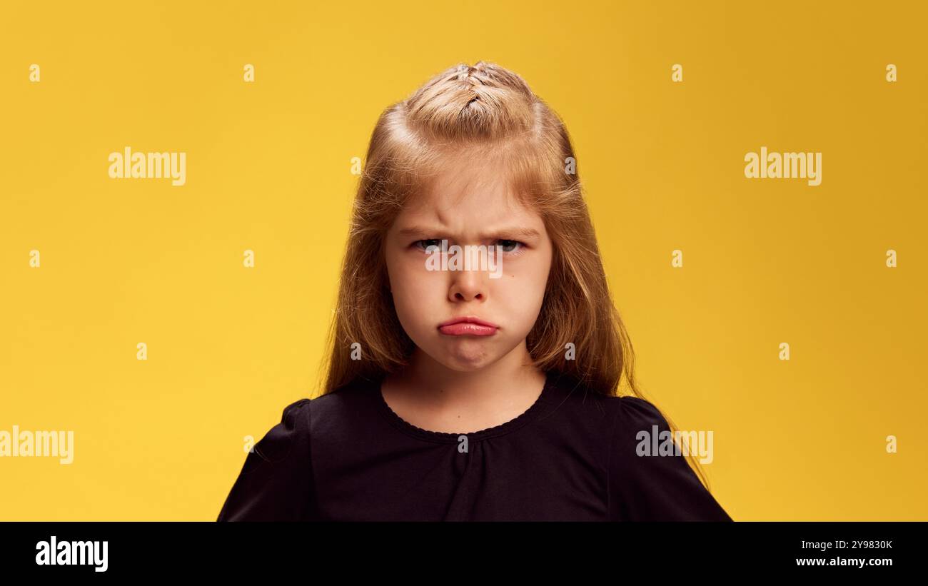 Staring directly at camera, girl frowns with sulky expression, her lips ...