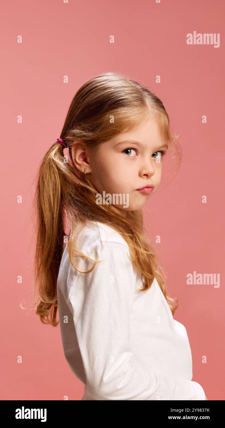 Pouting slightly, little girl gives side glance with playful ...
