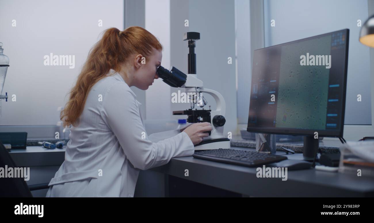 Medical science lab: Female microbiologist looks under microscope ...