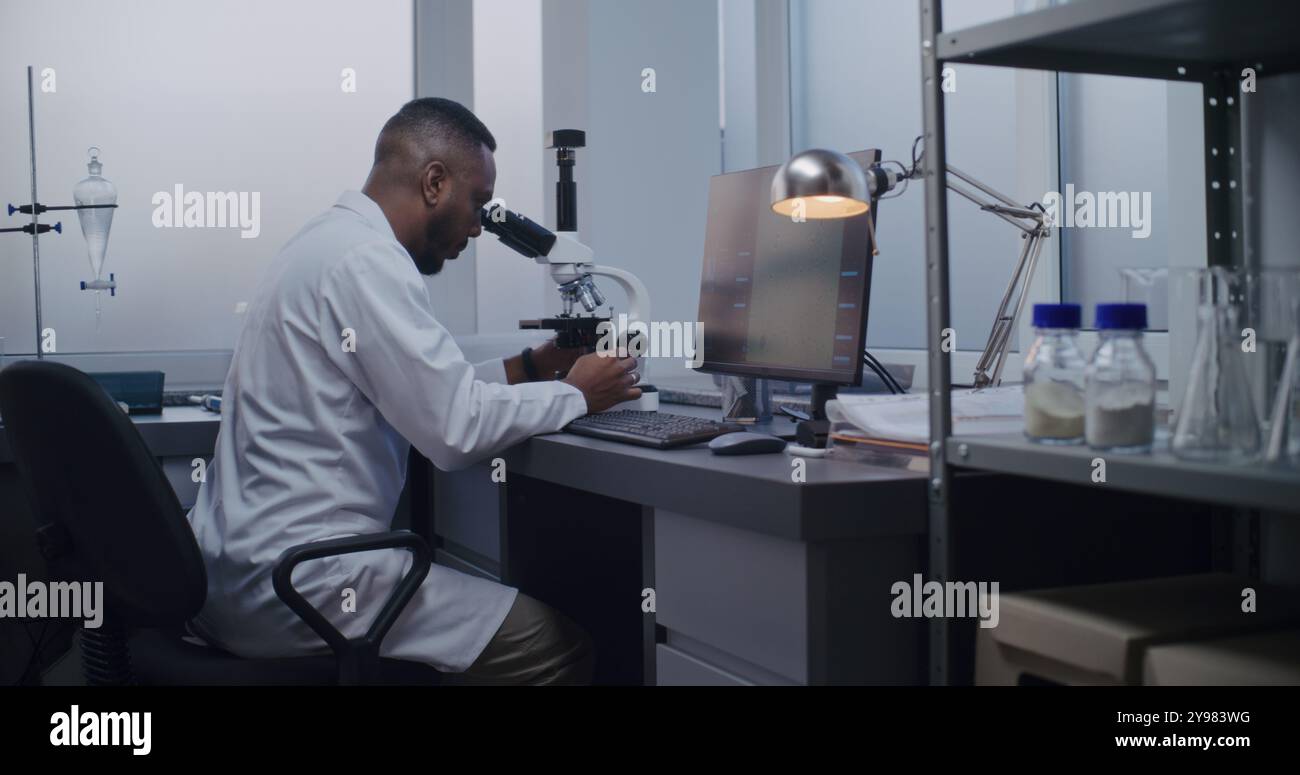 Medical science laboratory: African American microbiologist looks under ...
