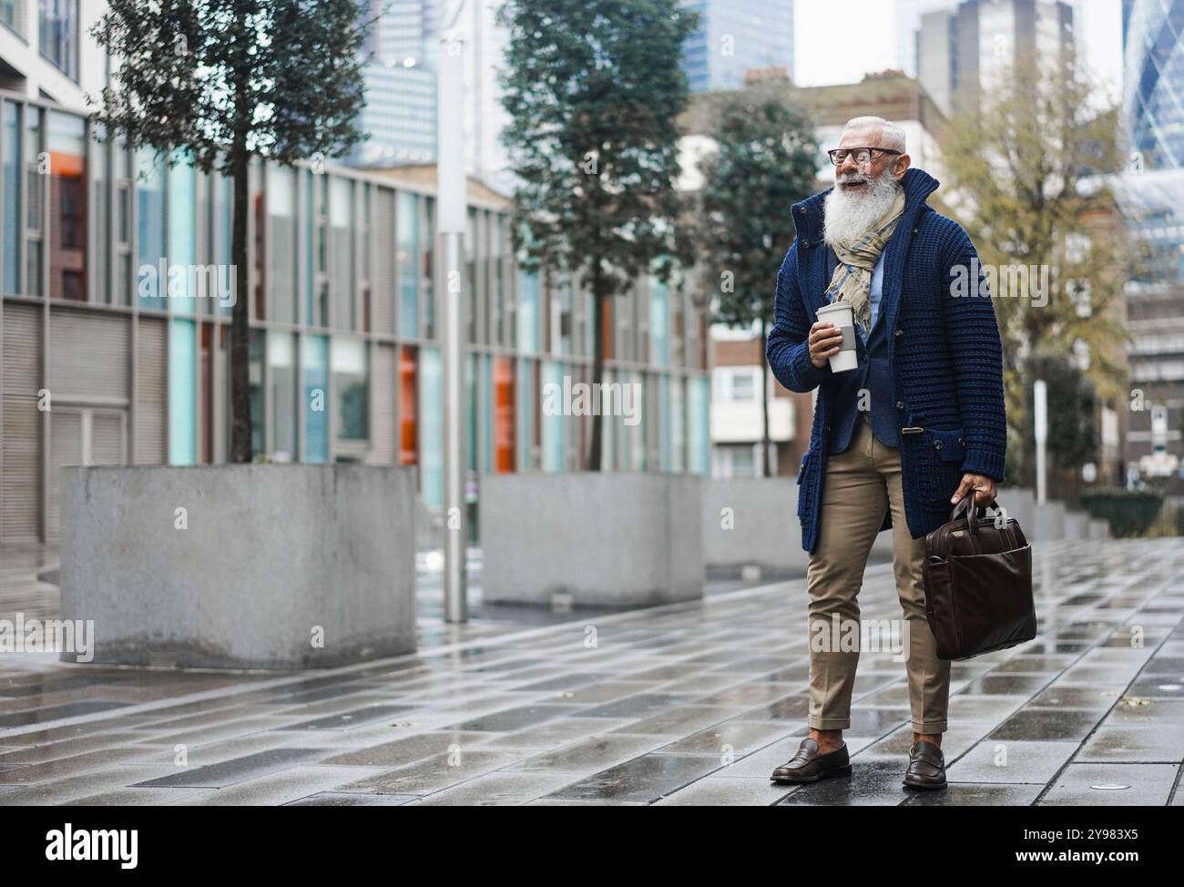 Happy business senior man walking to work on autumn rainy day - City ...