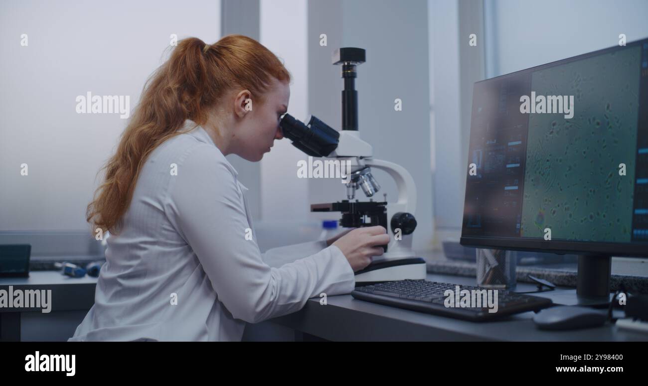 Medical science lab: Female microbiologist looks under microscope ...