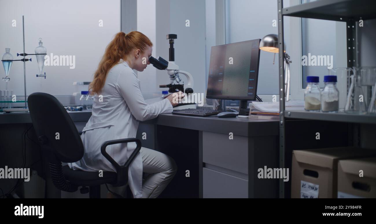 Medical science lab: Female microbiologist looks under microscope ...