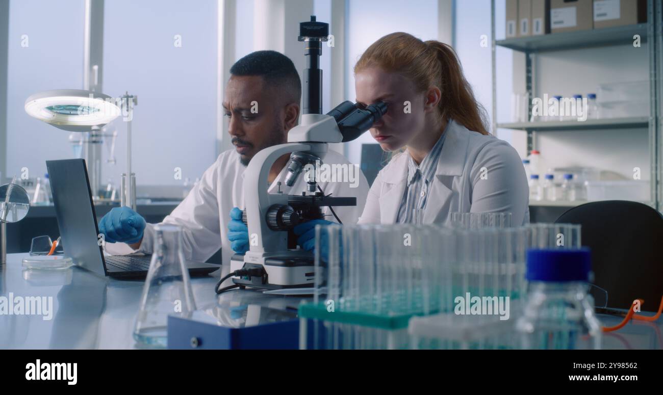 Advanced medical science laboratory: Two diverse scientists using ...