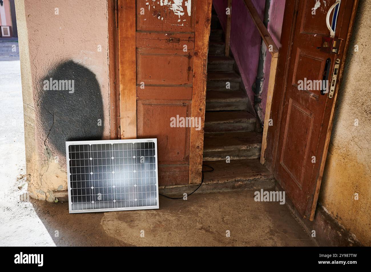 Photovoltaic solar panel at weathered, textured wall with peeling paint ...