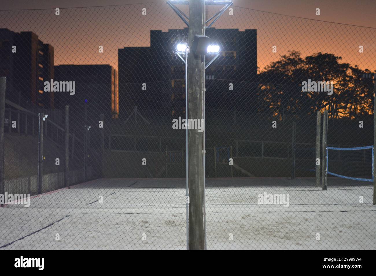 Beach tennis court with building in the background and night lighting ...
