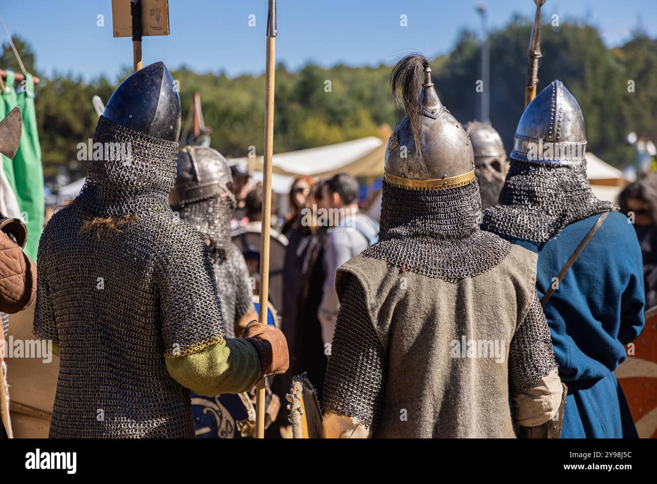 Medieval reenactors wearing chainmail armor are seen from behind ...