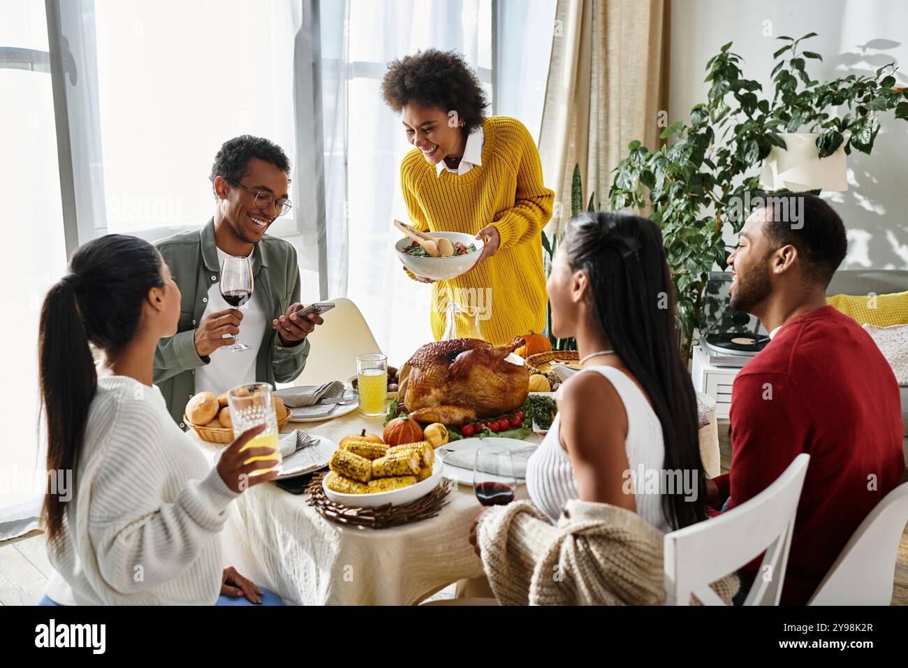 A lively group of friends enjoys Thanksgiving dinner, sharing food and ...