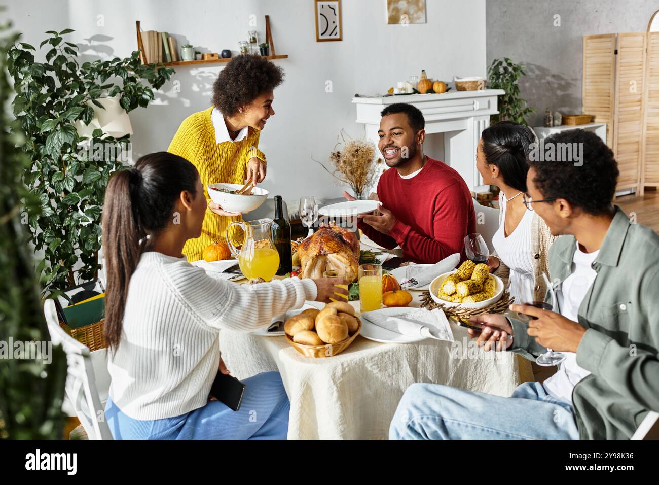 A group of friends gathered around a table, joyfully sharing a Thanksgiving feast with laughter ...