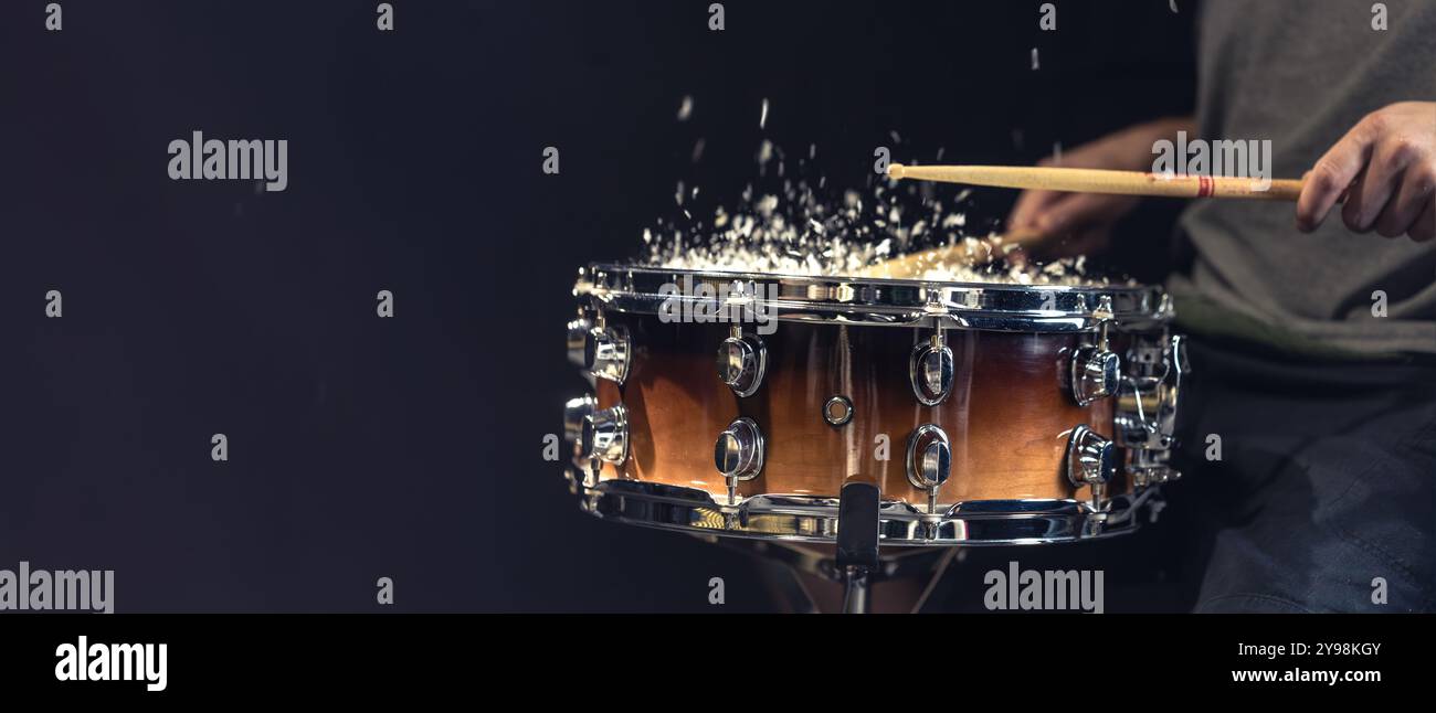 Drum sticks hitting snare drum with splashing water on black background ...