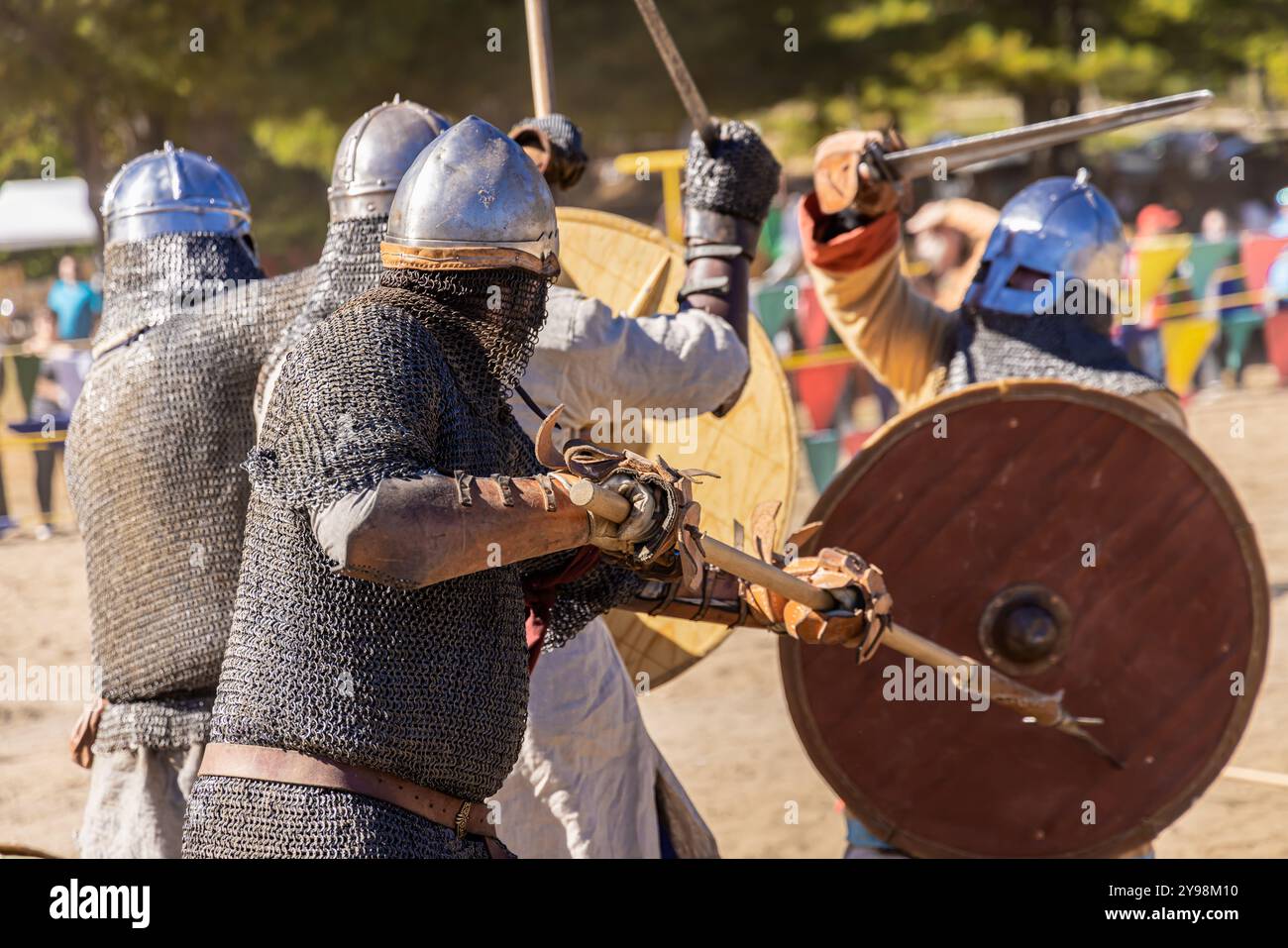 Medieval reenactors wearing chainmail armor are battling with swords and shields during a public ...