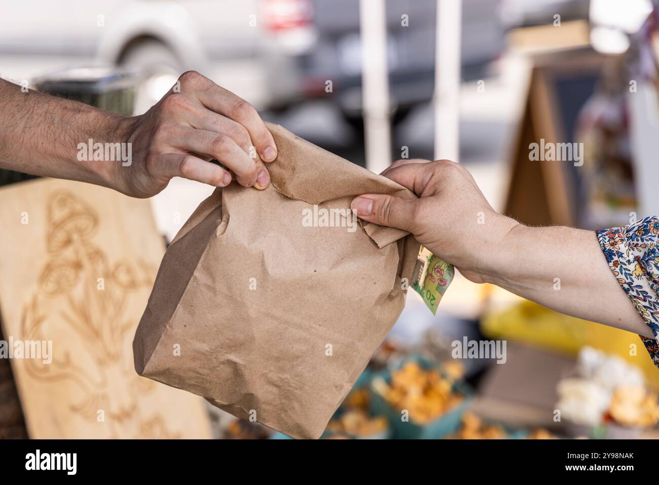 Farmer is giving a brown paper bag of fresh produce to a customer at a ...