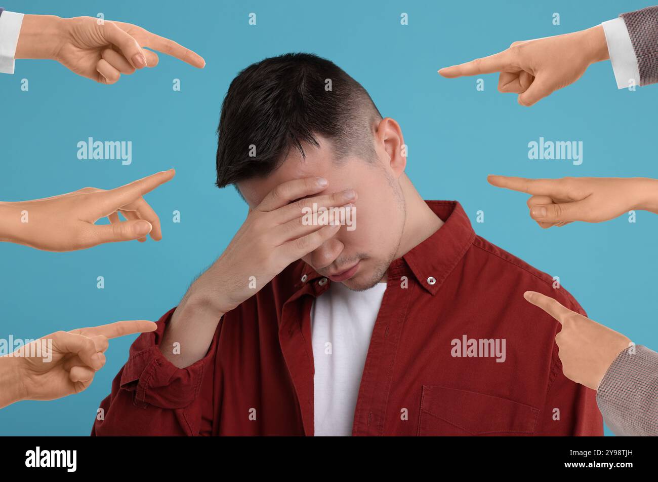 People pointing at embarrassed man on light blue background Stock Photo ...