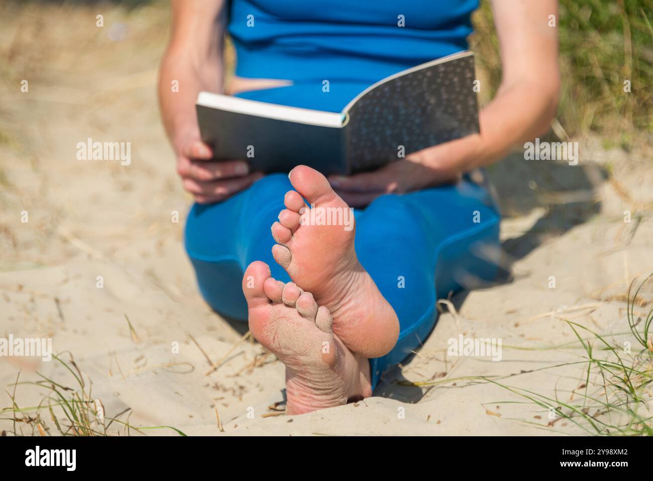close up of woman sitting on beach reading a book, sandy feet Stock ...