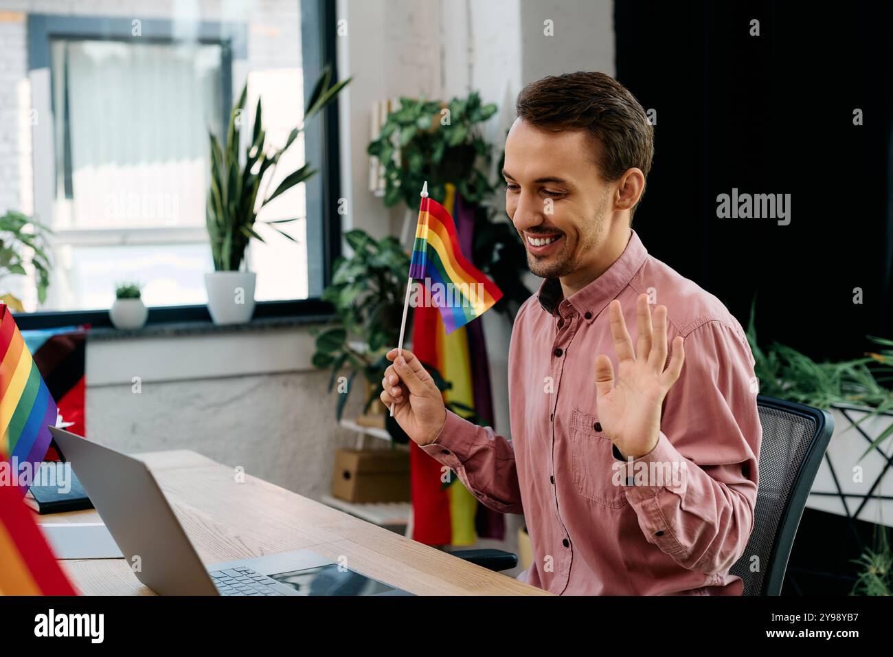 Cheerful man working in office surrounded by colorful pride flags Stock ...