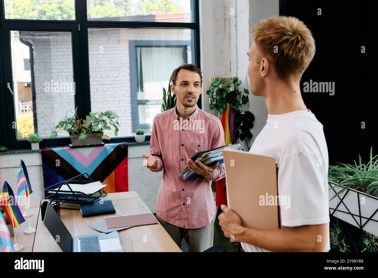 Two handsome men are having an animated conversation in a bright ...