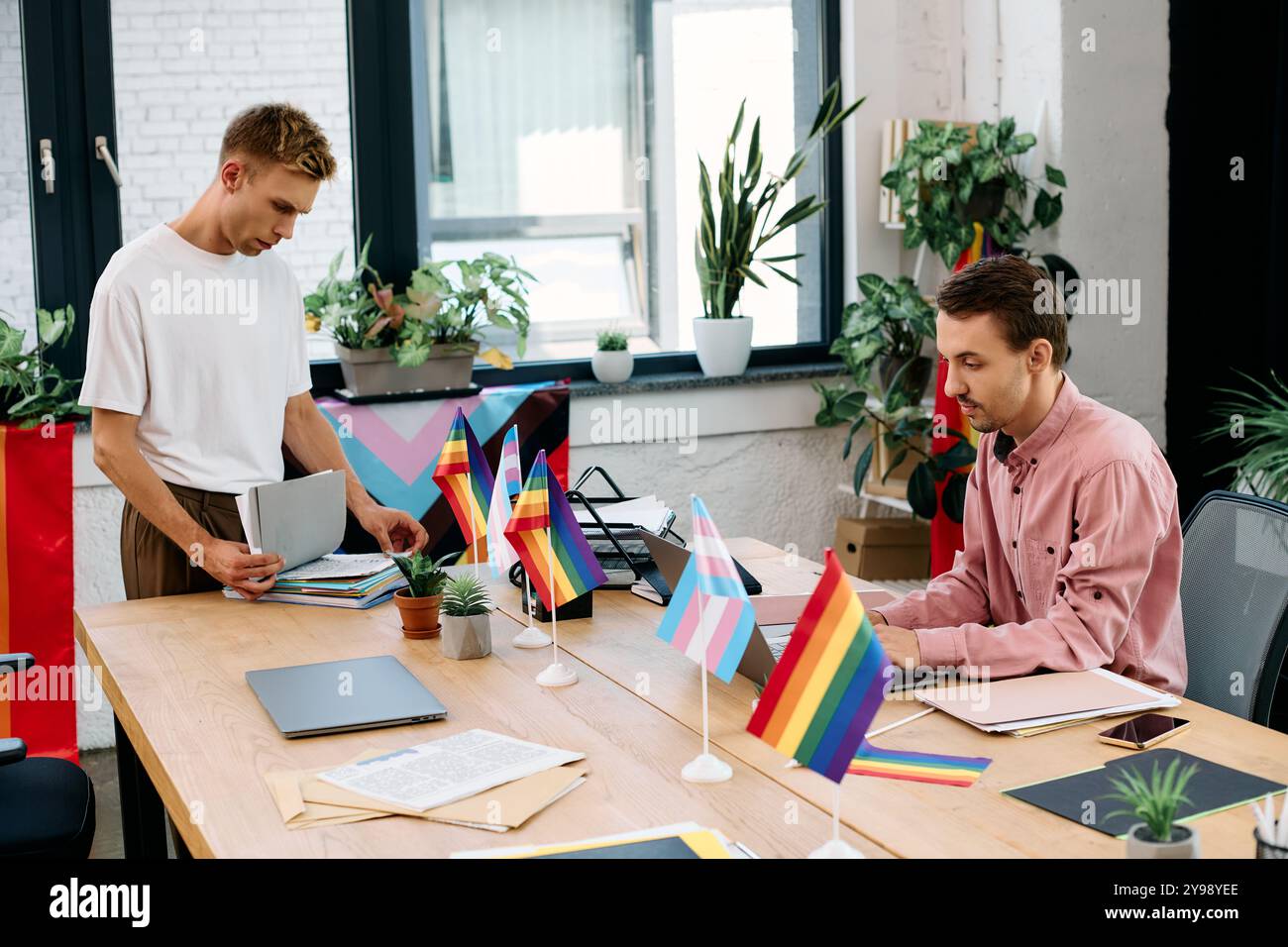Two men sort paperwork in a lively, plant filled space adorned with ...