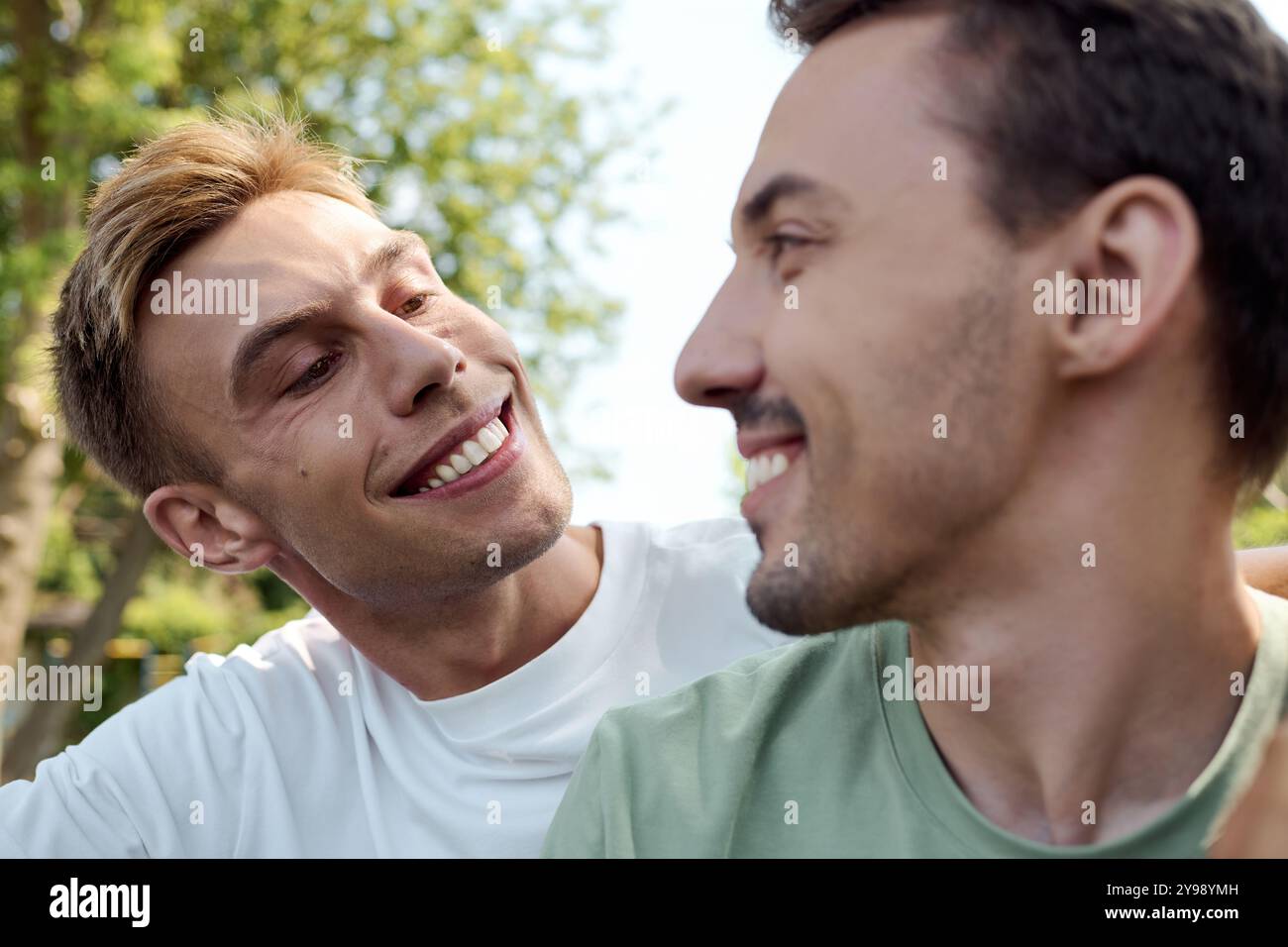 Two charming men share smiles and laughter while embracing in a vibrant ...