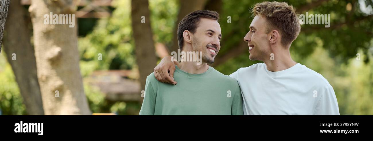 Two smiling men enjoy a sunny afternoon in a beautiful park, embracing ...
