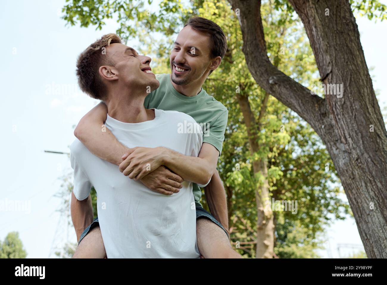 Two men celebrate a sunny day, playfully embracing and enjoying each ...
