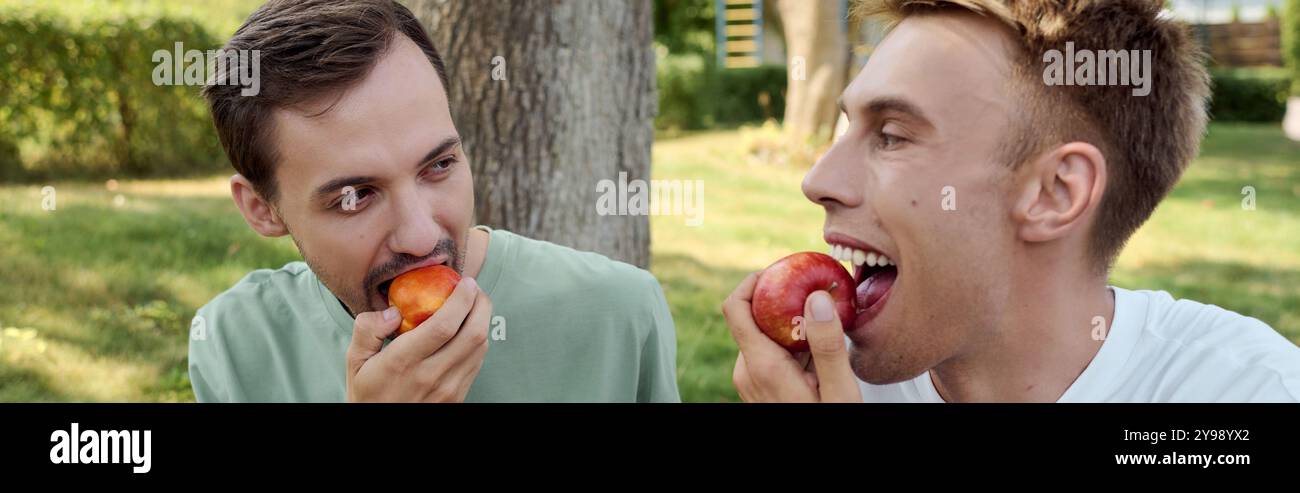 A joyful couple shares a lighthearted moment, savoring apples together ...