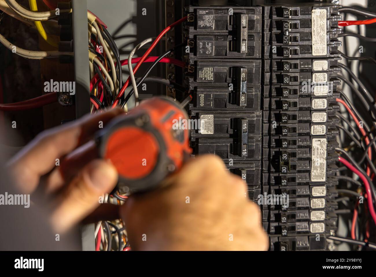 Electrician is installing an electrical circuit breaker in a power ...
