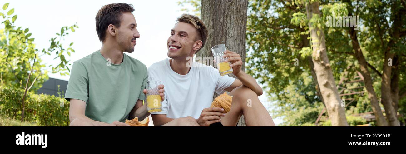 Two handsome men sit together, sharing laughter and chilled beverages ...
