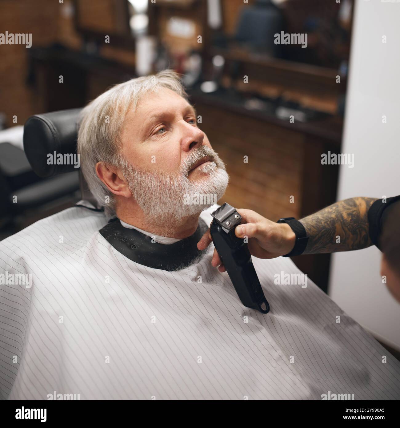 Barber carefully using clipper to finish detailing client beard ...