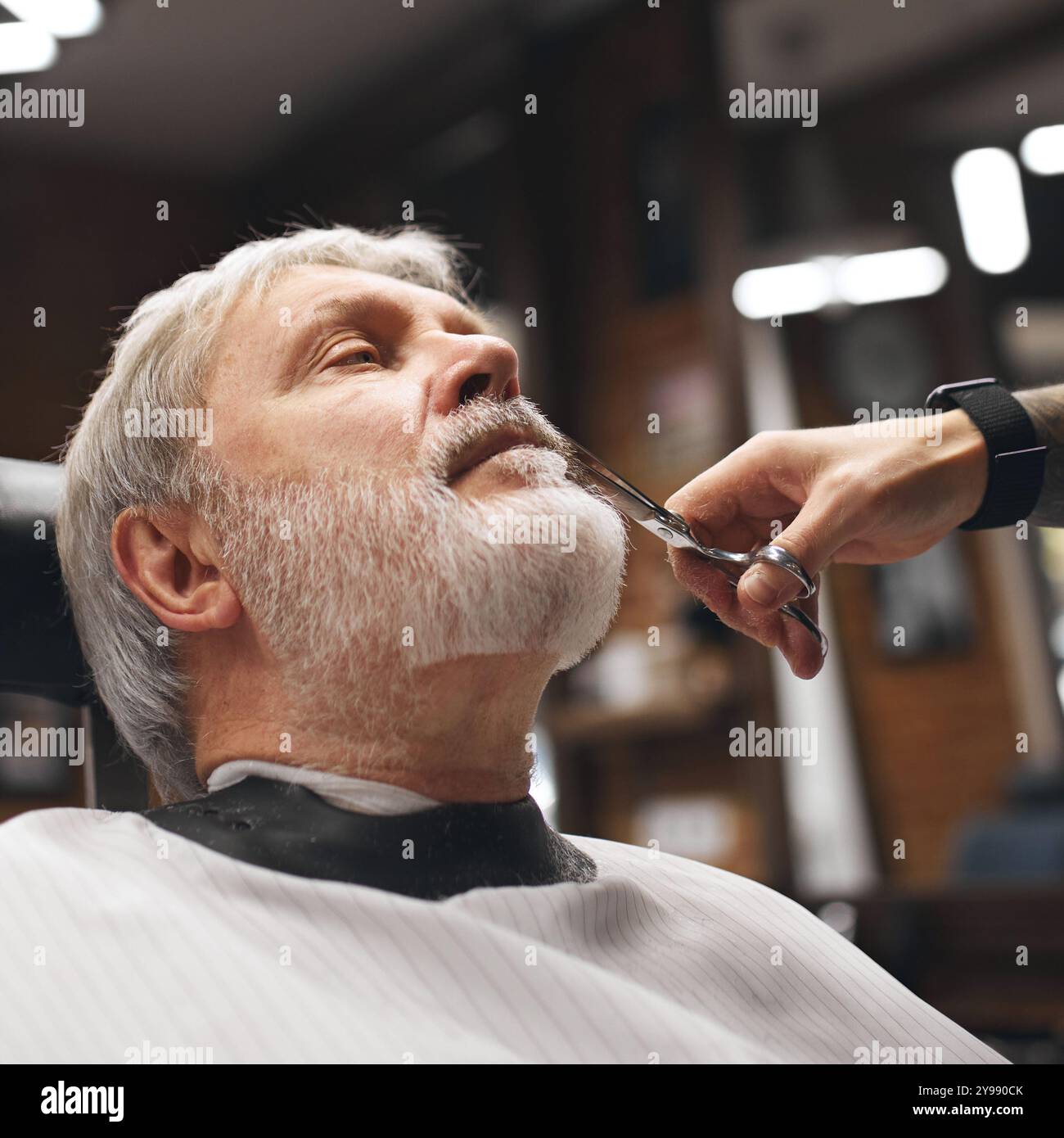 Barber gently trimming older man mustache with scissors, focusing on ...