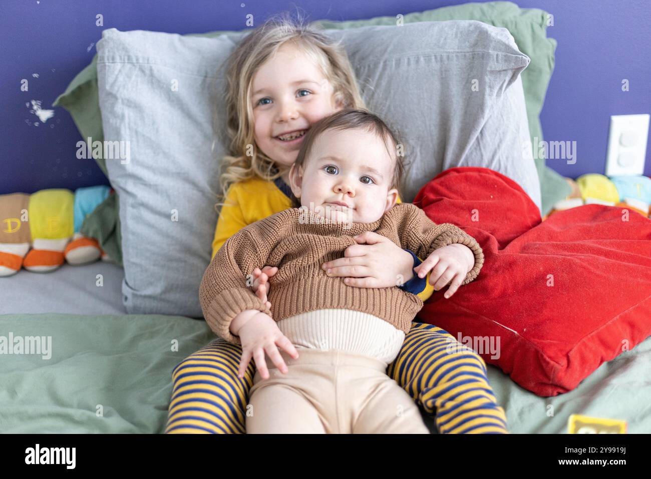 Big brother cuddles baby sister on cozy bed, sharing joyful smiles ...