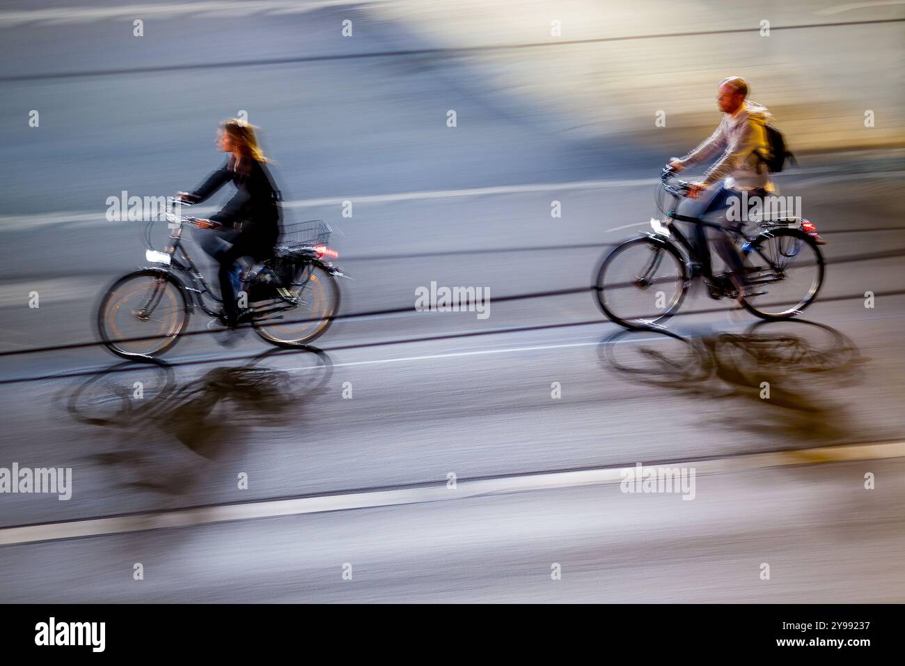 Dynamic panning photo capturing two cyclists riding through a city at ...