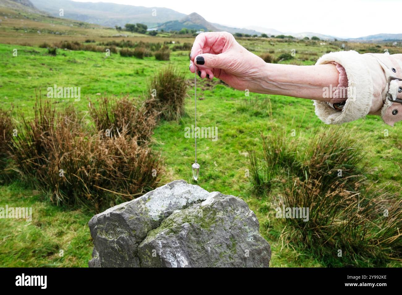 Female dowsing a standing stone using a crystal pendulum - John Gollop ...