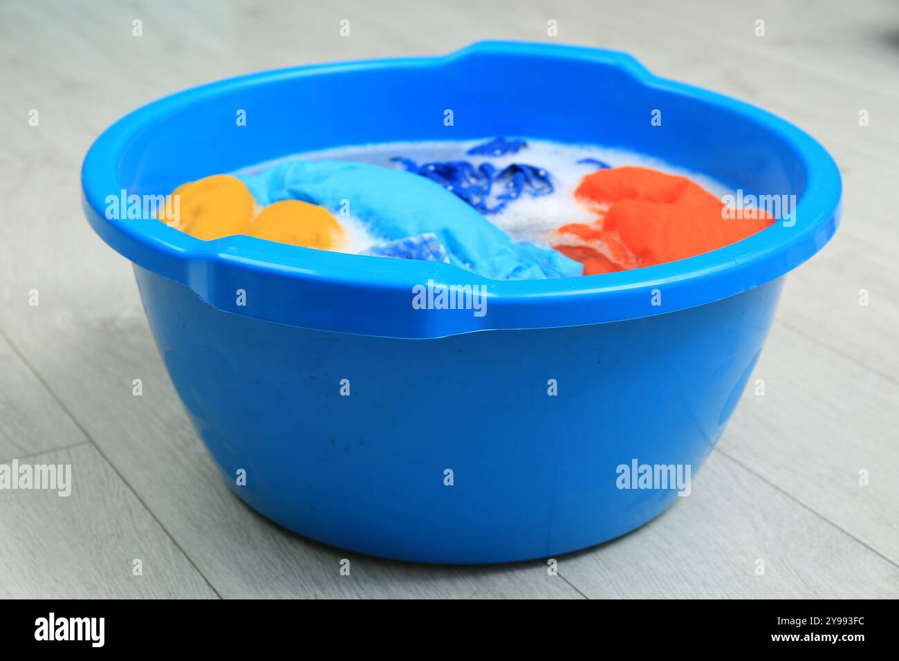 Basin with colorful clothes on floor, closeup. Hand washing laundry ...