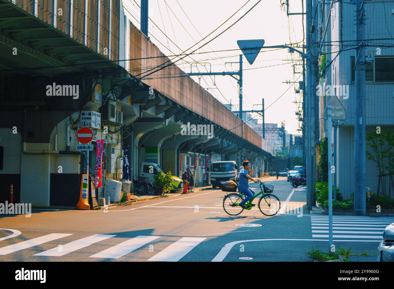 A cyclist rides through a quiet Tokyo street, framed by an underpass ...