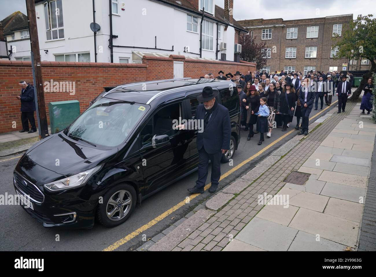 Close relatives, friends and family walk behind the funeral car ...