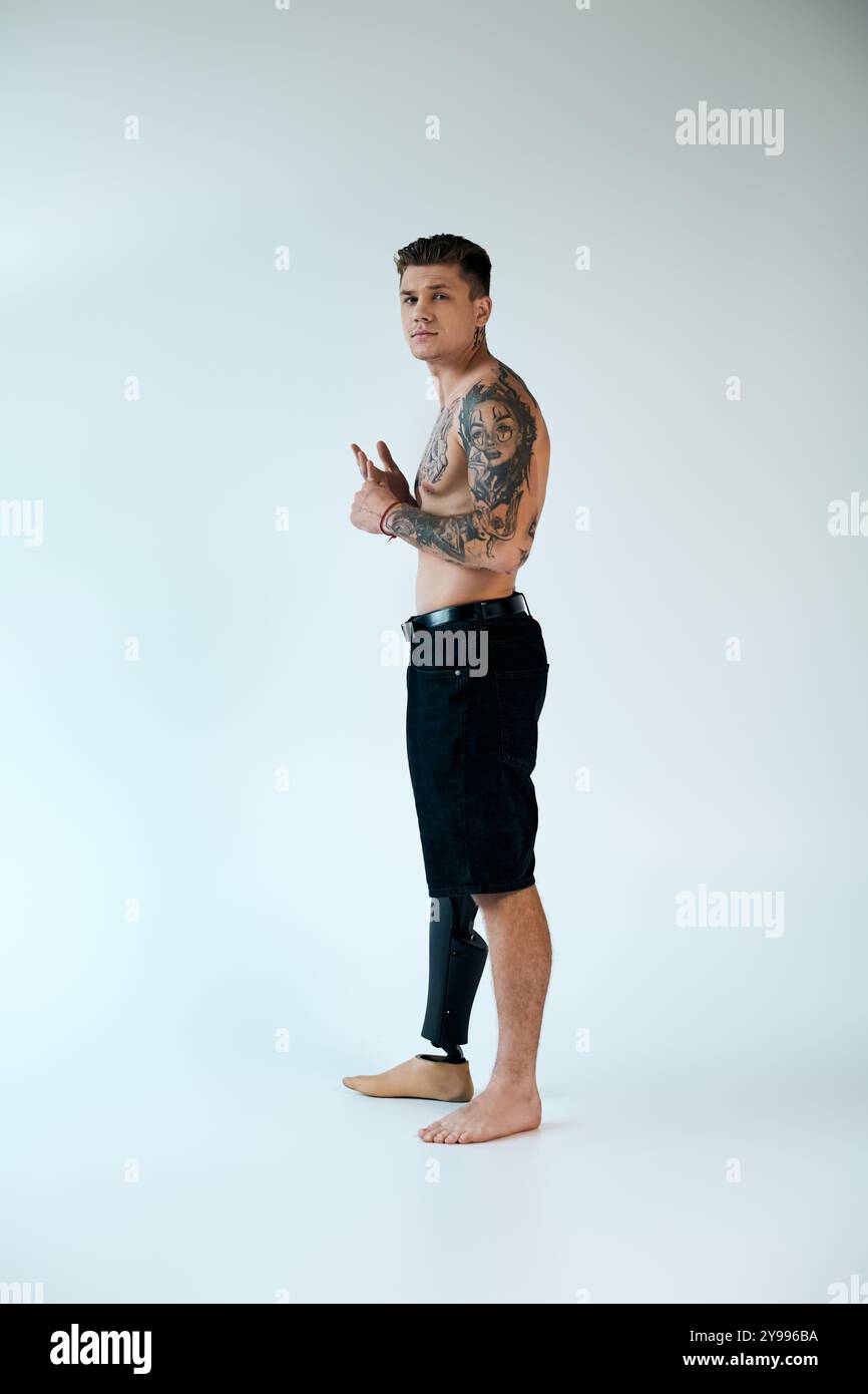A tattooed young man stands proudly in a studio, showcasing his ...