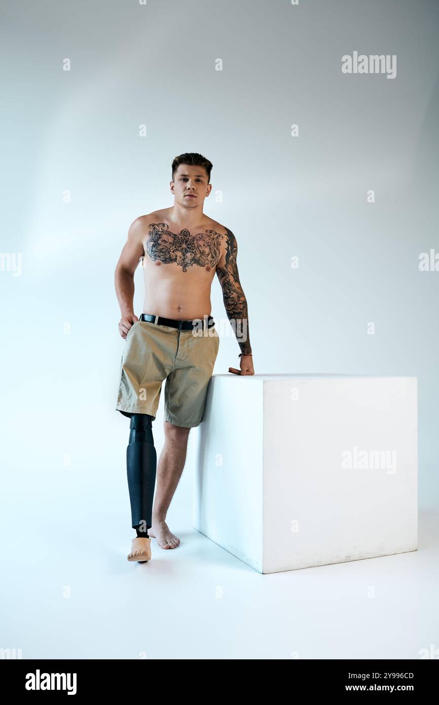 A confident young man with tattoos stands proudly in a studio ...