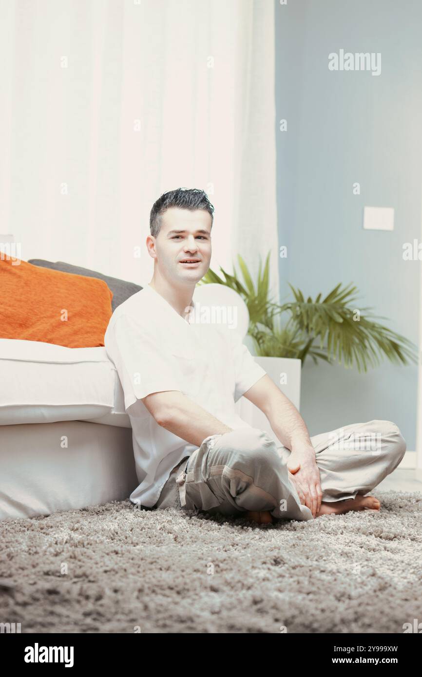 Man is sitting on the floor in a cross legged position, expressing ...