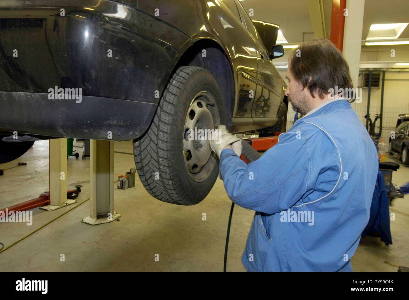 employee at the car shop manually changing tire on a vehicle manually ...