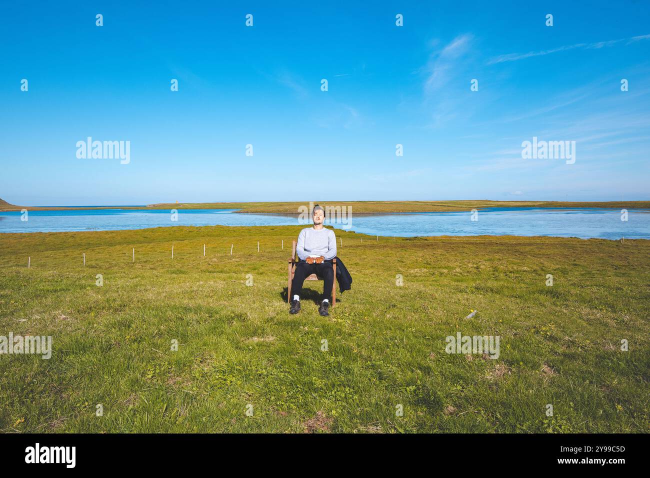 Boy relaxes on a wooden chair, sunbathing with eyes closed, soaking in ...