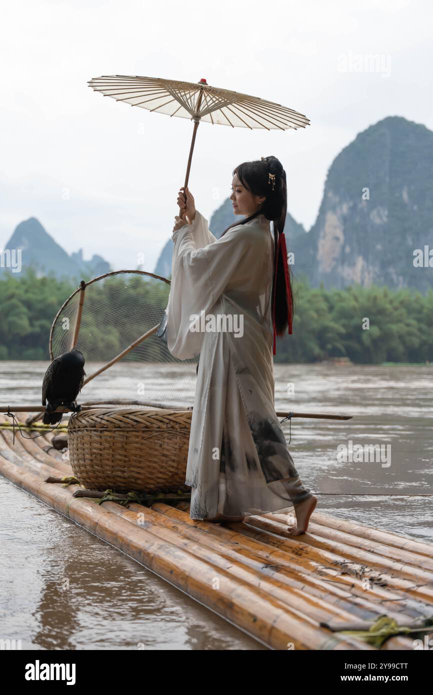 Hanfu girl with deng looking at mountainous landscape from raft on Li ...
