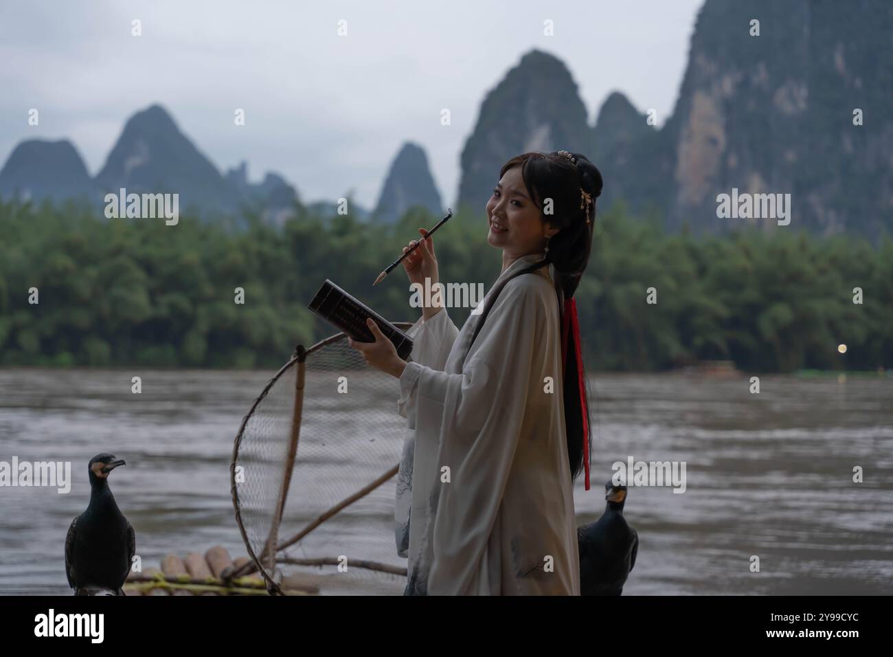 Medium shot of beautiful Hanfu lady with quill in front of scenic ...