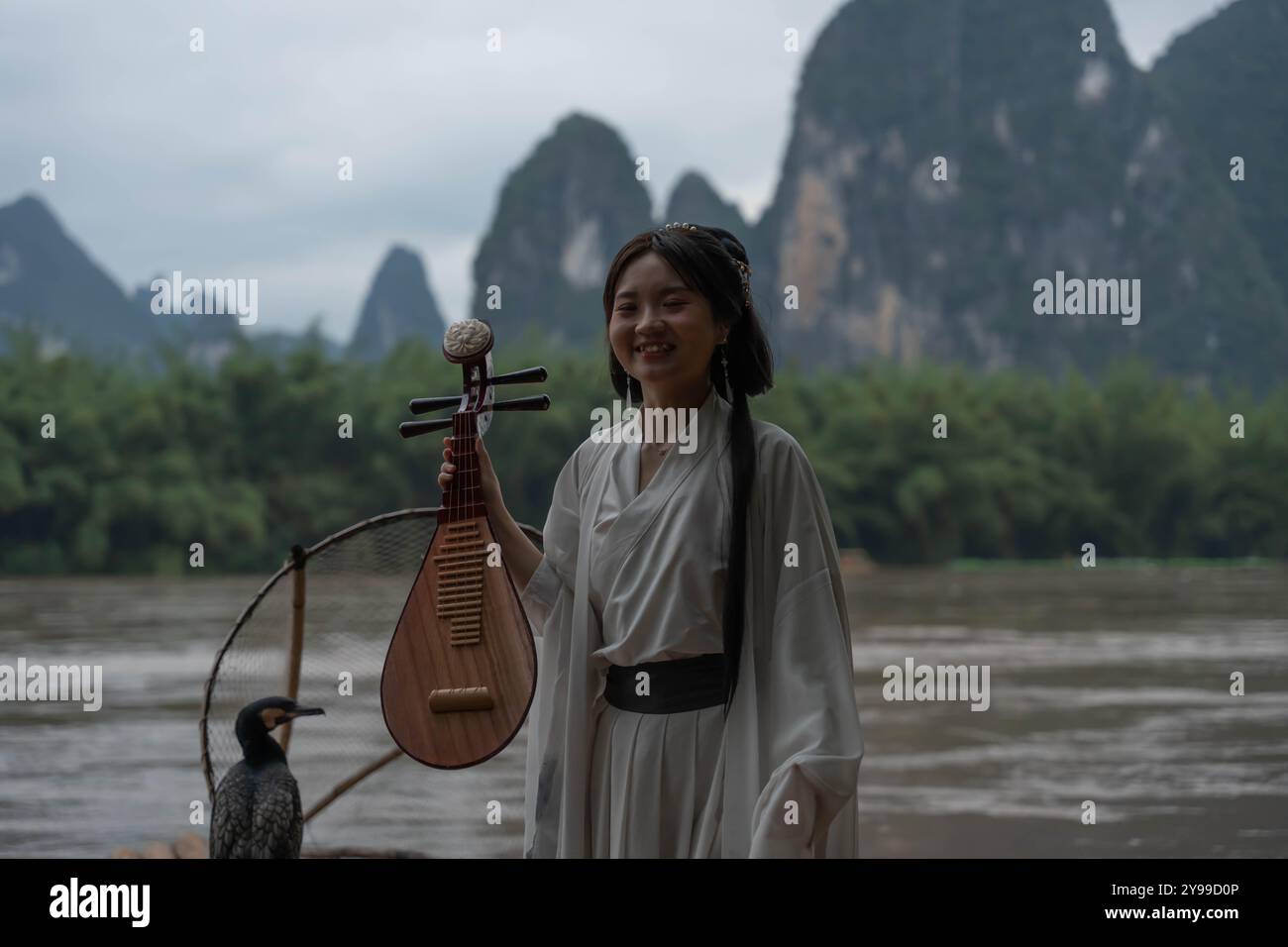 Hanfu girl smiling over Li River puts a pipa traditional instrument in ...