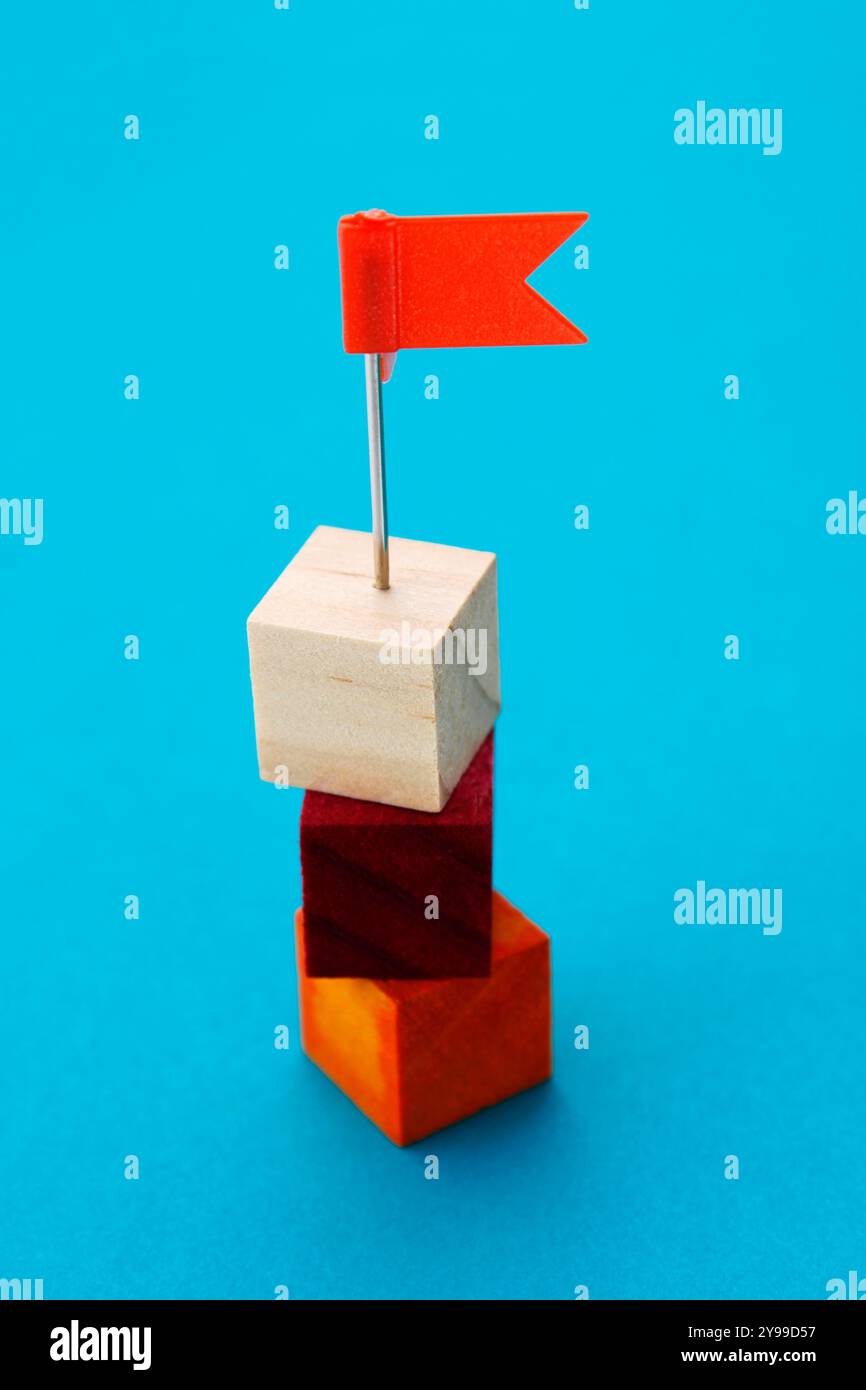 Flag shaped thumbtack overcoming levels formed with wooden cubes Stock ...